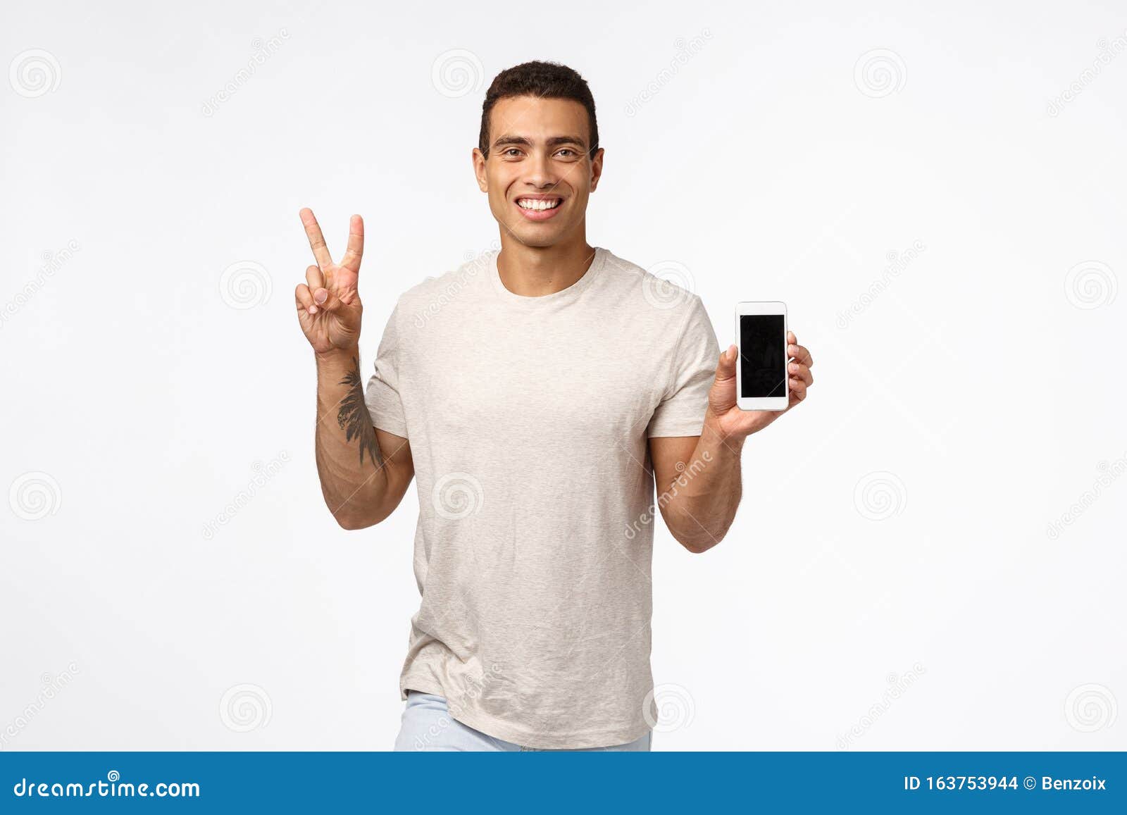Friendly Cheerful Handsome Man In Casual Outfit Holding Smartphone