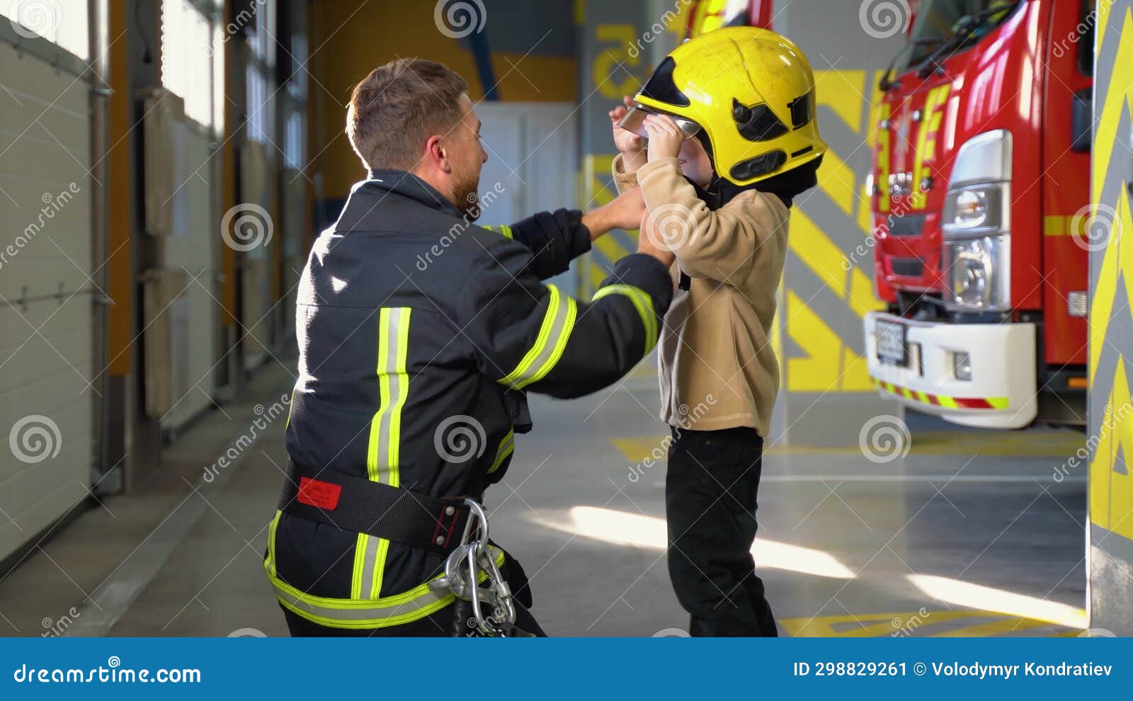 Friendly Firefighter Puts a Protective Helmet To a Little Boy Stock ...