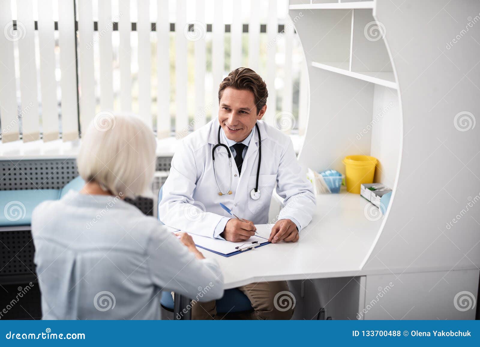 Friendly Practitioner Smiling while Looking at the Patient Stock Photo ...