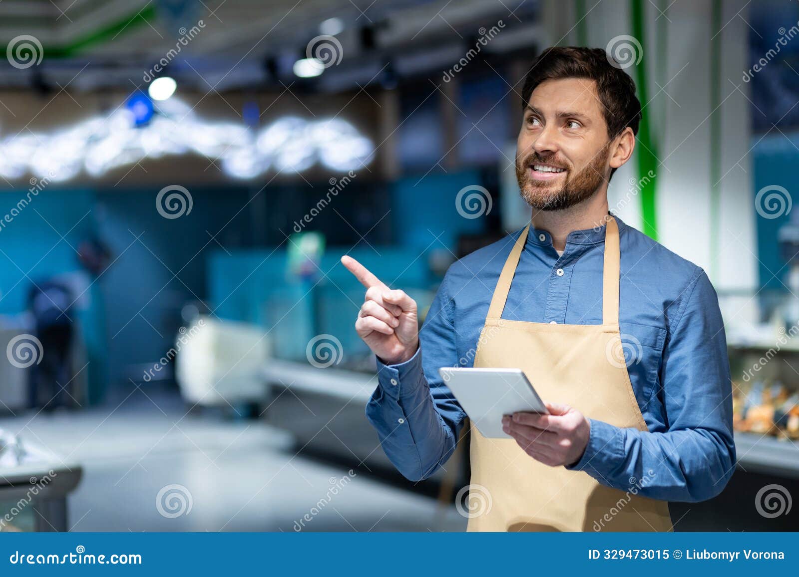 Friendly Shopkeeper Using Tablet in Grocery Store while Pointing and ...