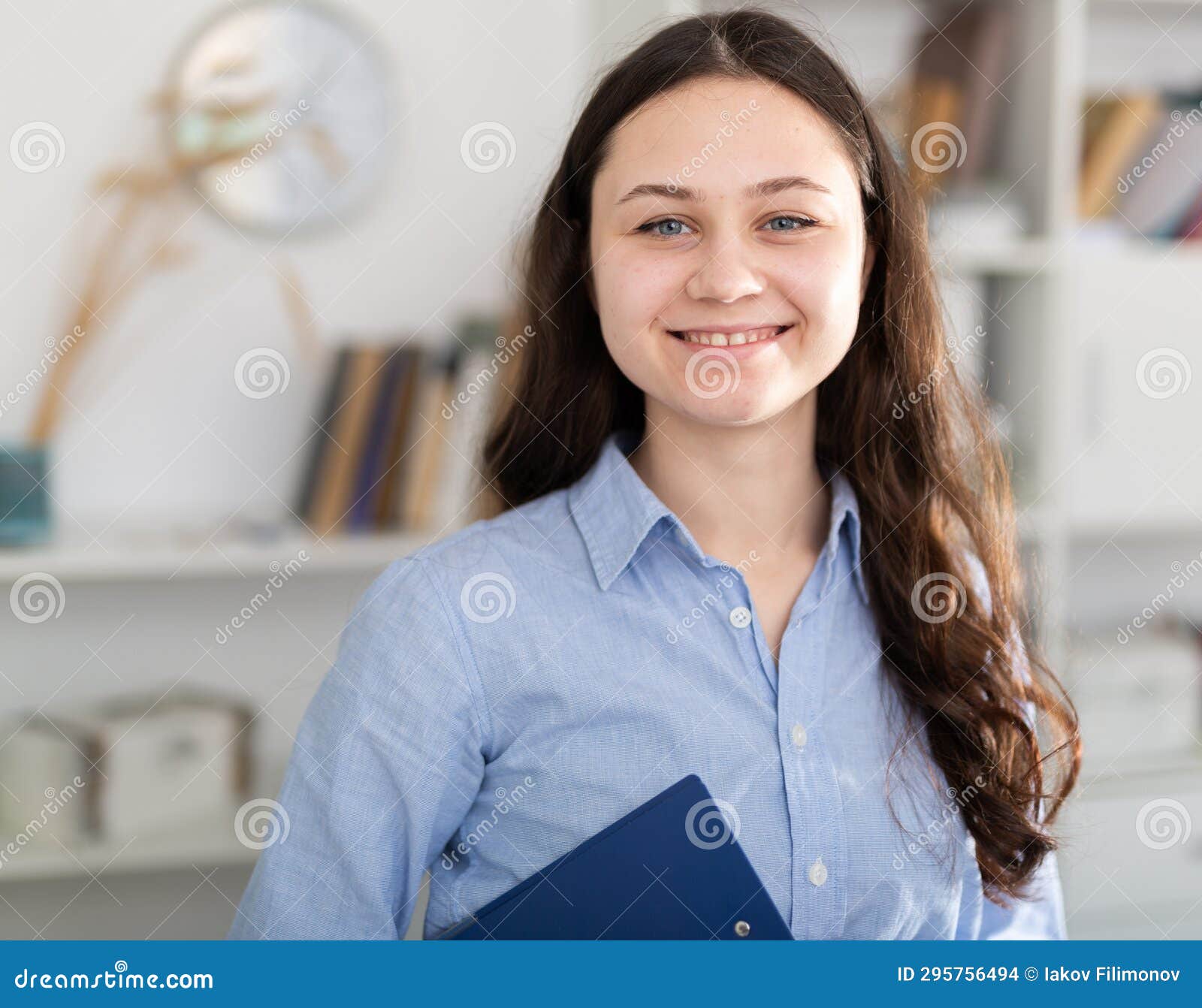 Friendly Woman with Blue Folder of Documents Stands in Office Stock ...