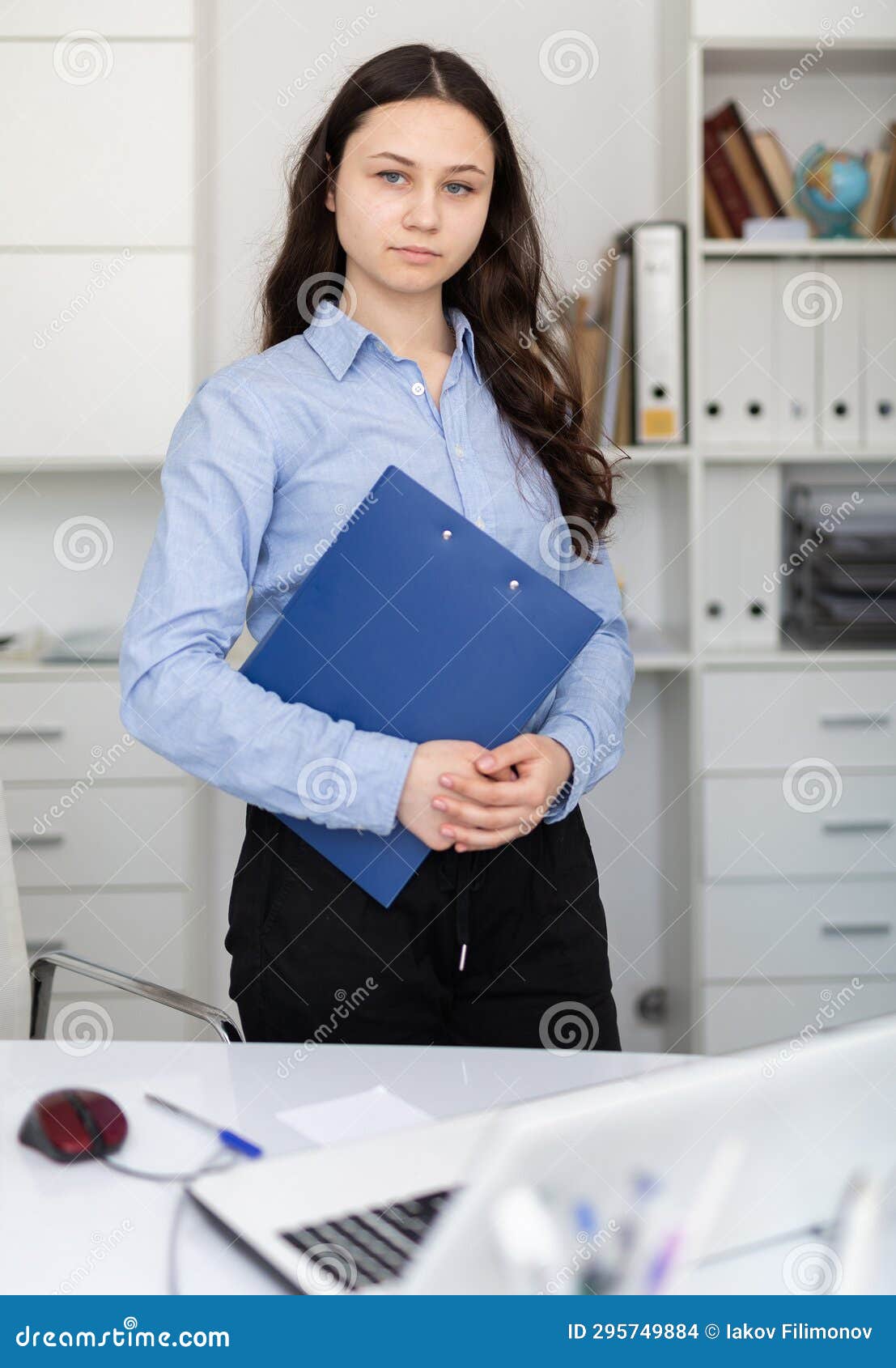 Friendly Woman with Blue Folder of Documents Stands in Office Stock ...