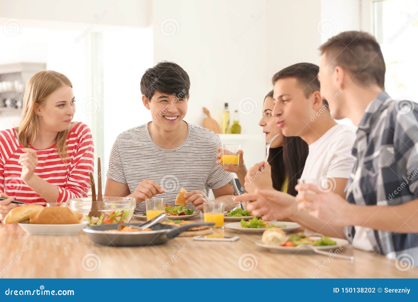 Friends Eating at Table in Kitchen Stock Photo - Image of food, female ...