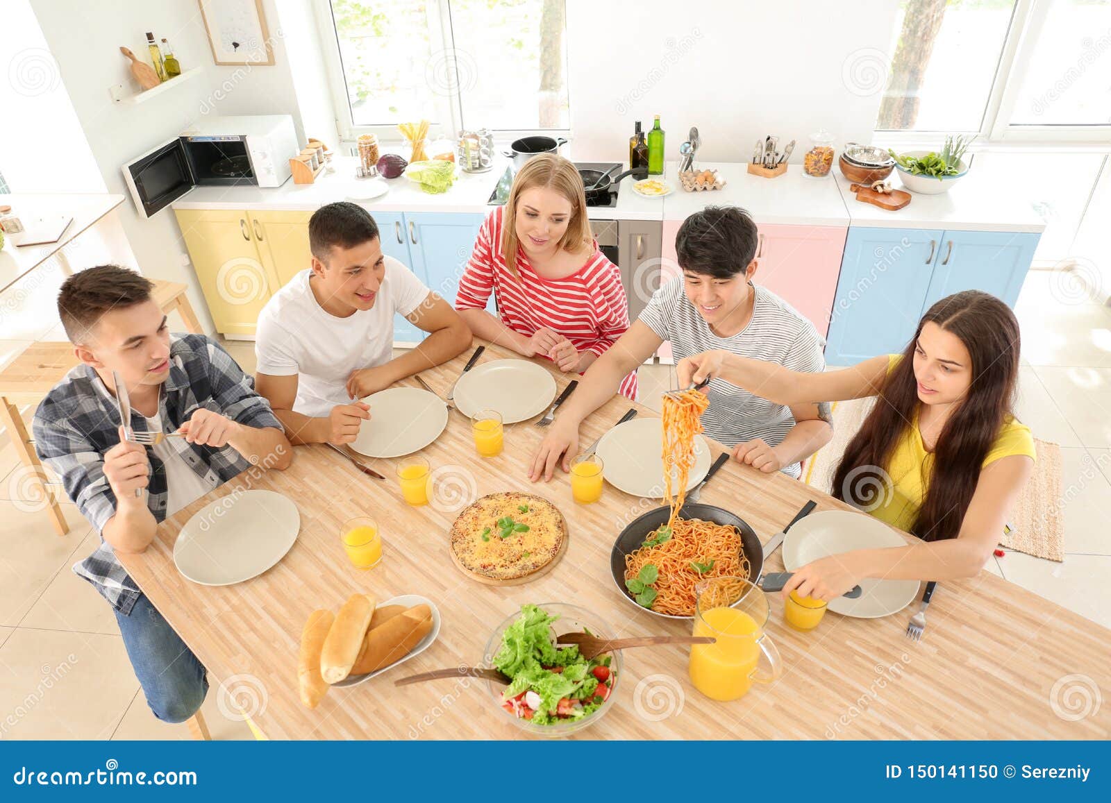 Friends Eating at Table in Kitchen Stock Photo - Image of cooking ...