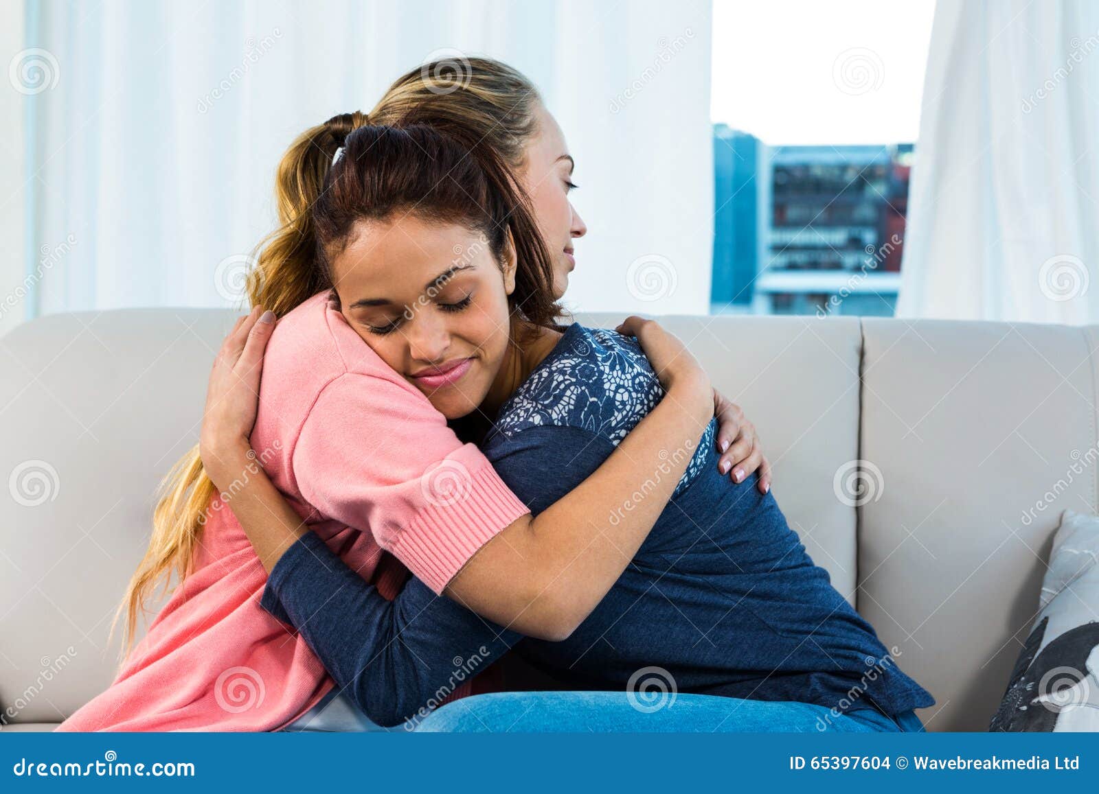 Friends hugging on sofa stock photo. Image of casual - 65397604