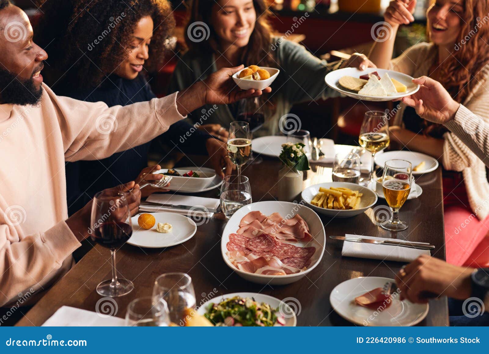 Friends Sharing Plates of Food in Restaurant Stock Photo - Image of ...
