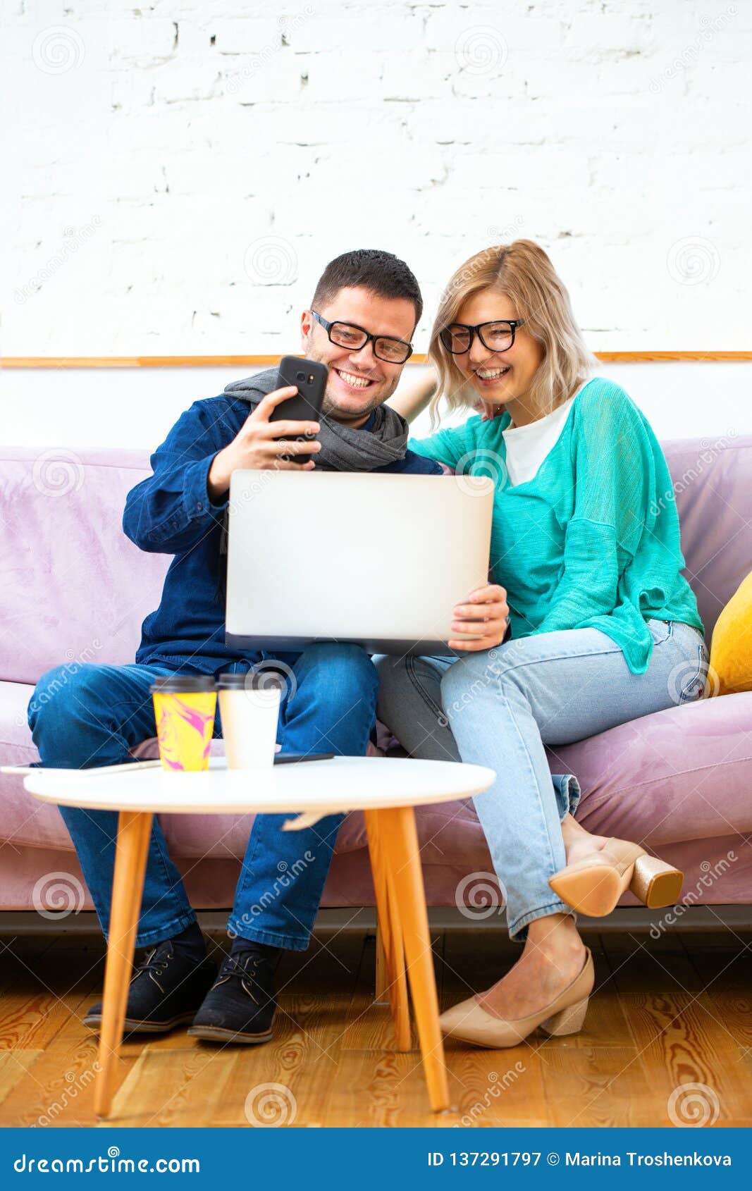 Friends Sit on the Couch, Chatting and Using a Smartphone, Desktop ...
