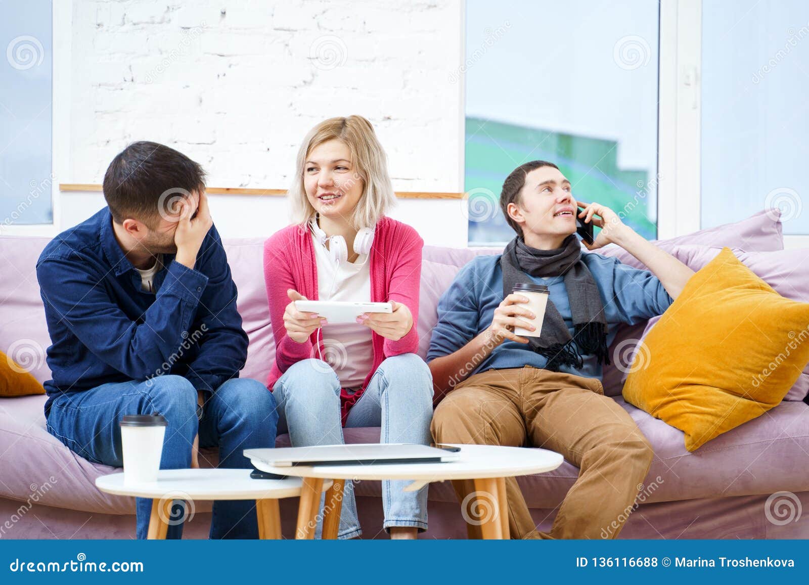 Friends Sit on the Couch, Chatting and Using a Smartphone, Desktop ...