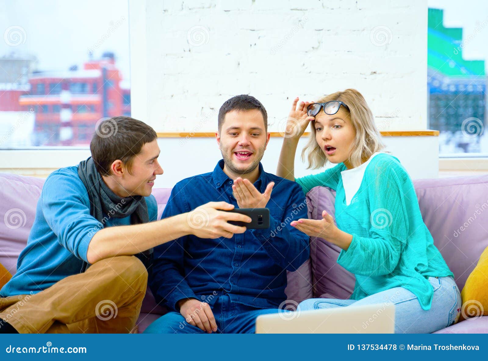 Friends Sit on the Couch, Chatting and Using a Smartphone, Desktop ...