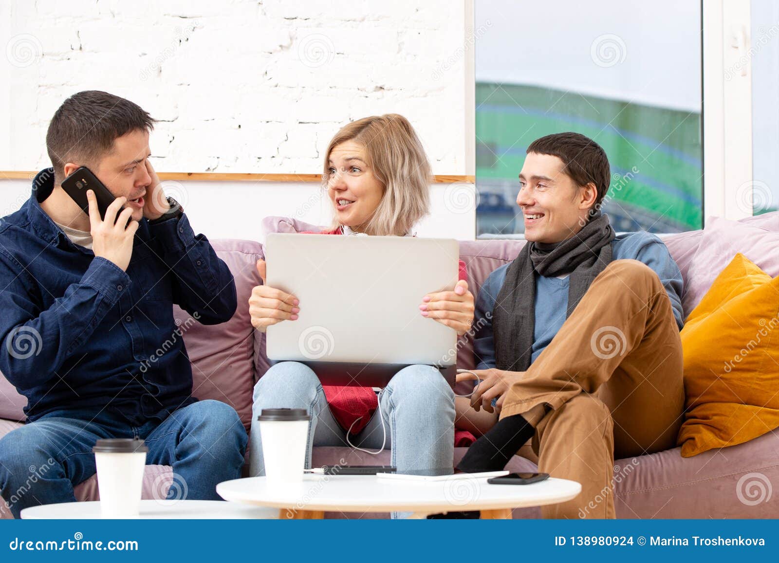 Friends Sit on the Couch, Chatting and Using a Smartphone, Desktop ...