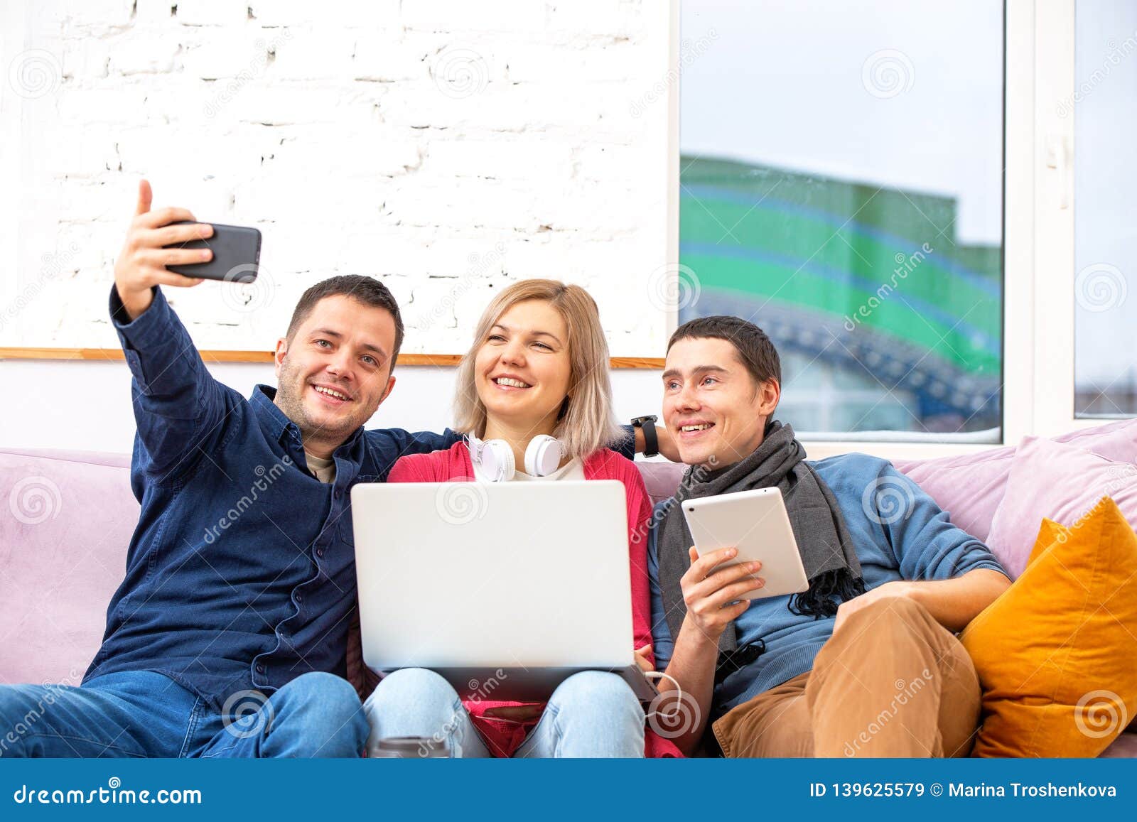 Friends Sit on the Couch, Chatting and Using a Smartphone, Desktop ...