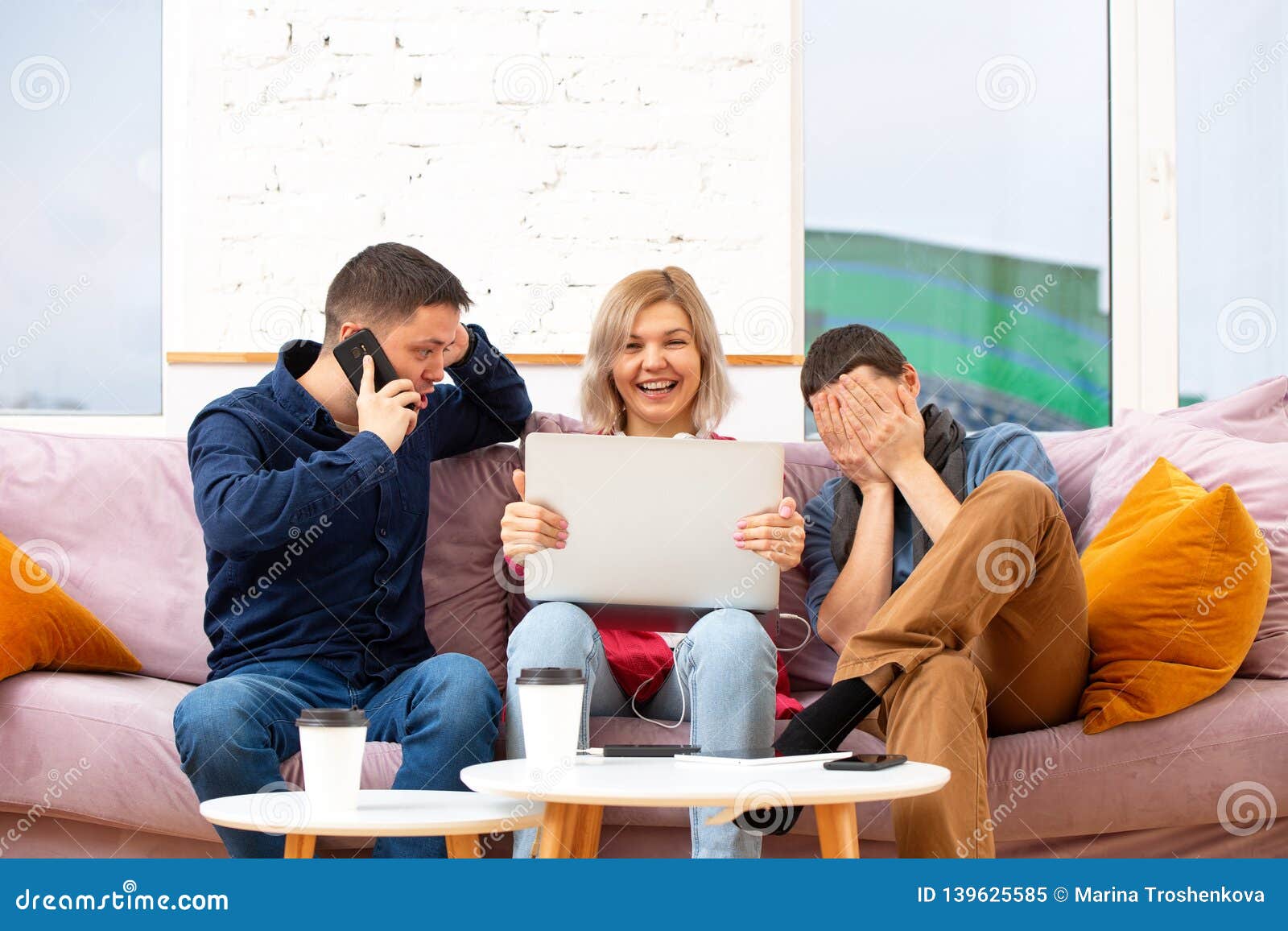 Friends Sit on the Couch, Chatting and Using a Smartphone, Desktop ...
