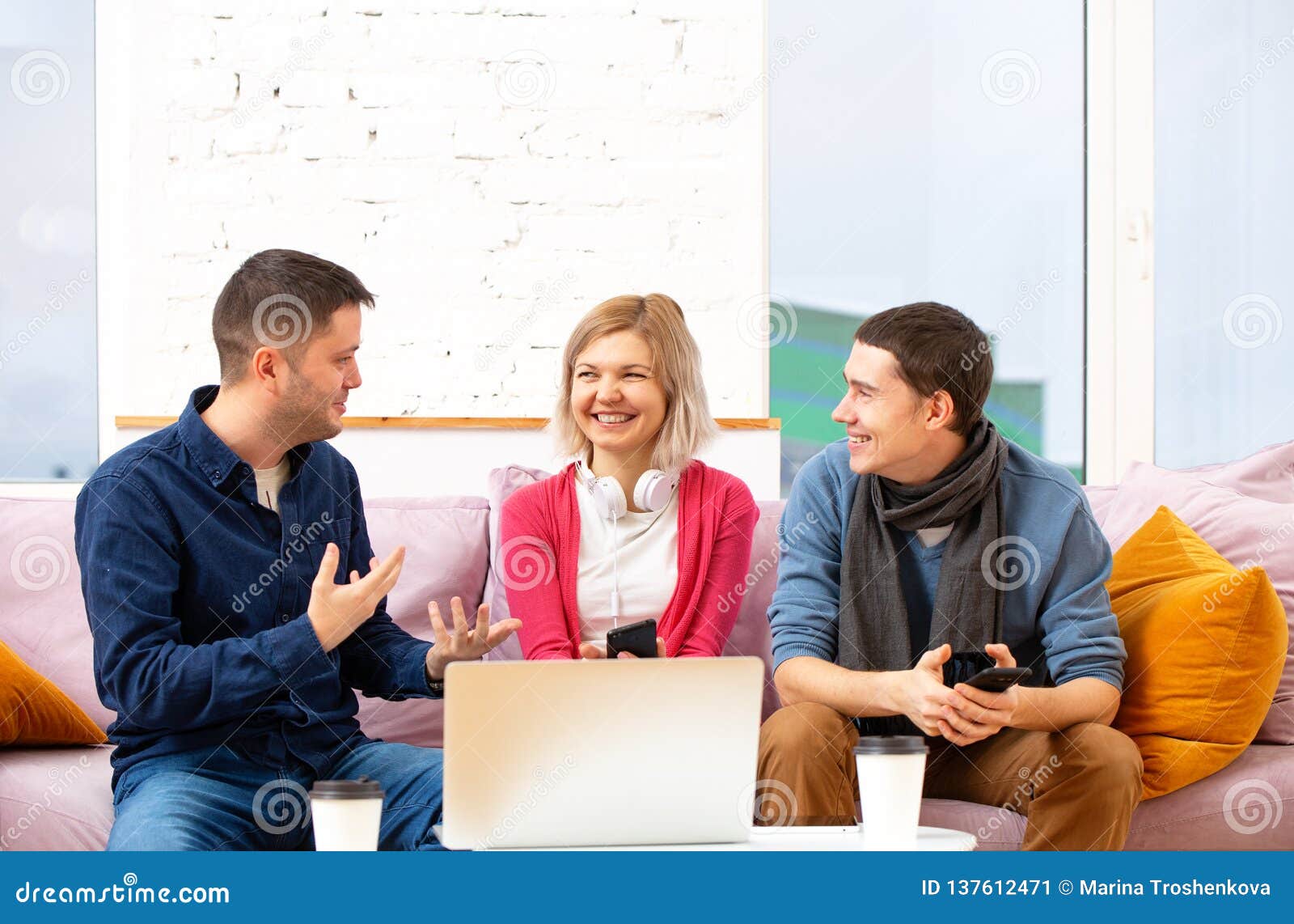 Friends Sit on the Couch, Chatting and Using a Smartphone, Desktop ...