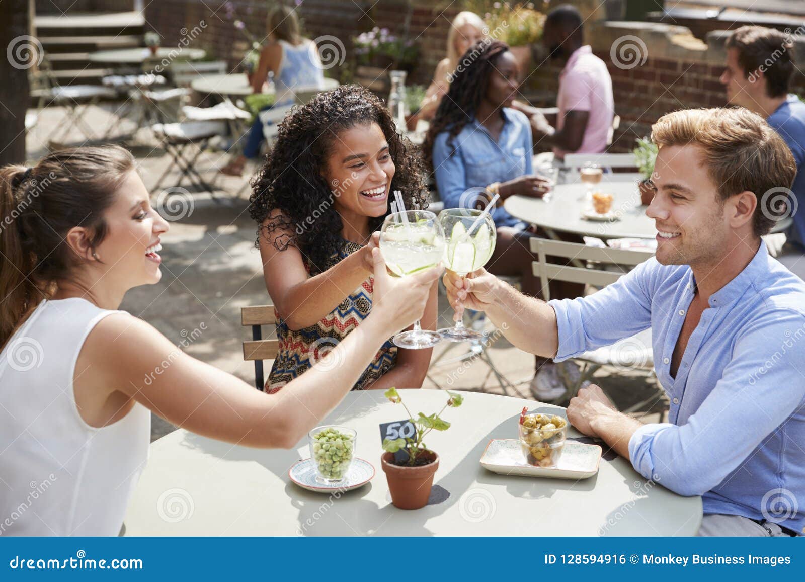 Friends Sitting at Table in Pub Garden Making Toast Together Stock ...