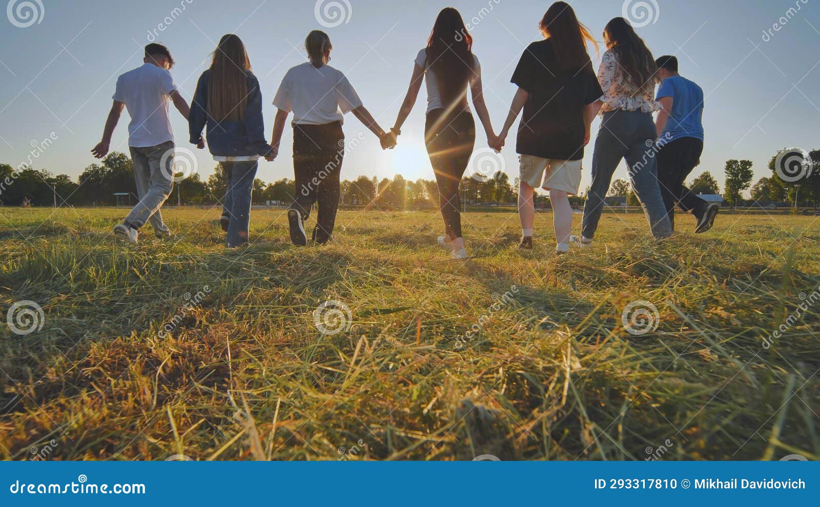 Friends at Sunset Holding Hands Walking Towards the Sun. Stock Photo ...