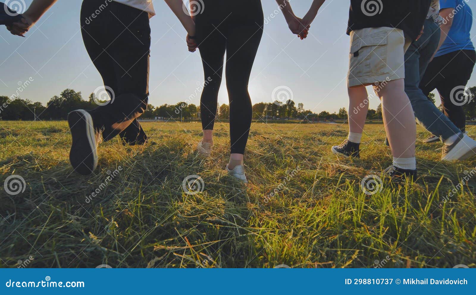 Friends at Sunset Holding Hands Walking Towards the Sun. Stock Image ...