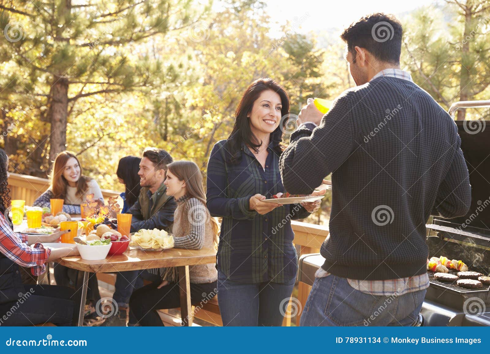 Friends at a Table and Two Talking by Grill at a Barbecue Stock Photo ...