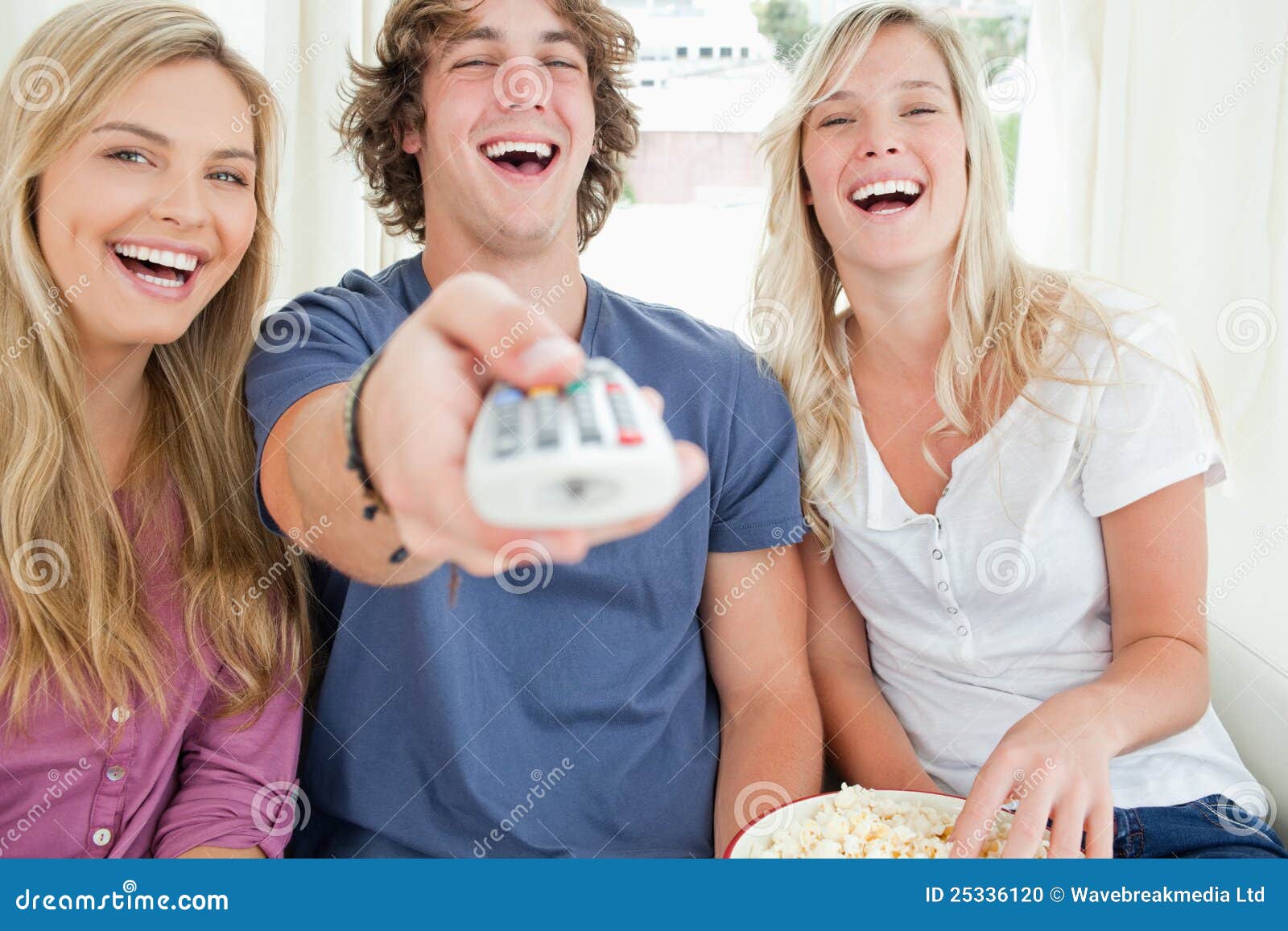 Friends Using the Remote To Work the Tv As they Laugh Stock Photo ...
