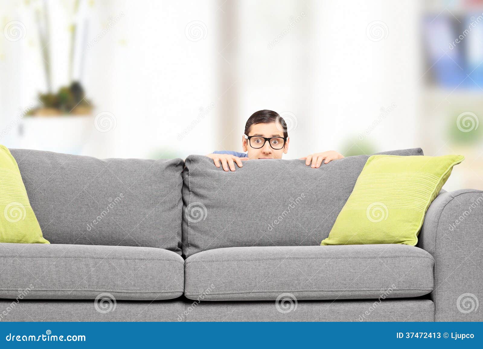 Frightened Man Hiding Behind a Sofa Stock Image - Image of peek, room ...