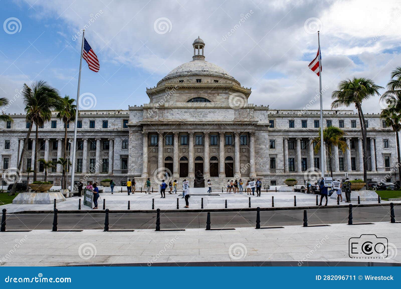 The Front Entrance of a Building with Some Columns and Two Flags on ...