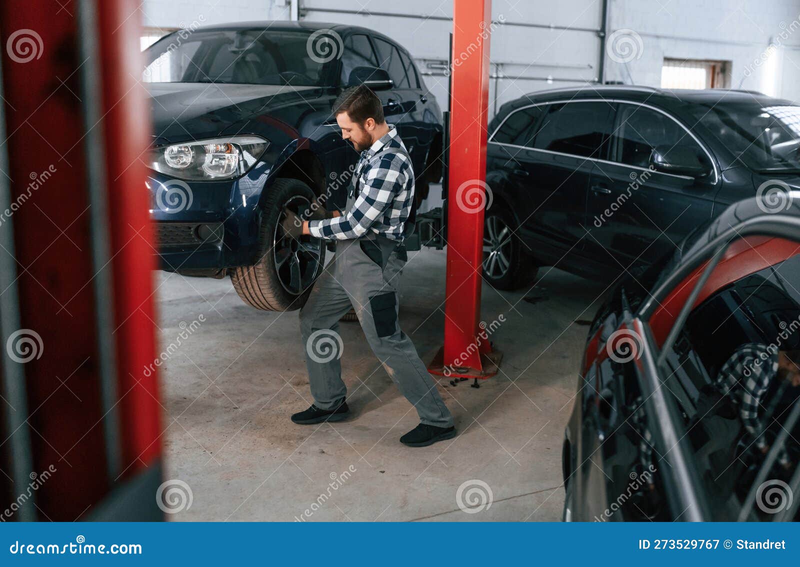 Front Left Wheel is Changing. Man in Uniform is Working in the Auto ...