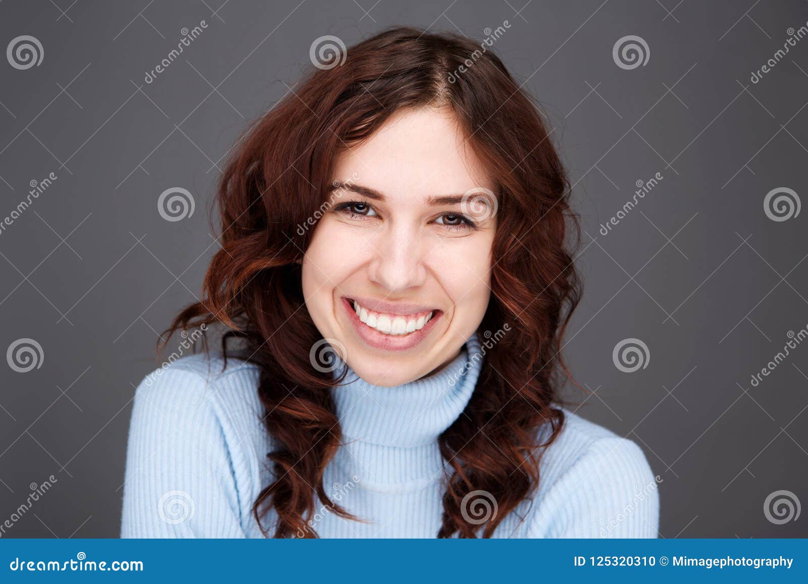 Front Portrait Of Happy Young Woman Smiling Against Gray Background ... Front Portrait Of Happy Young Woman Smiling Against Gray Background ...