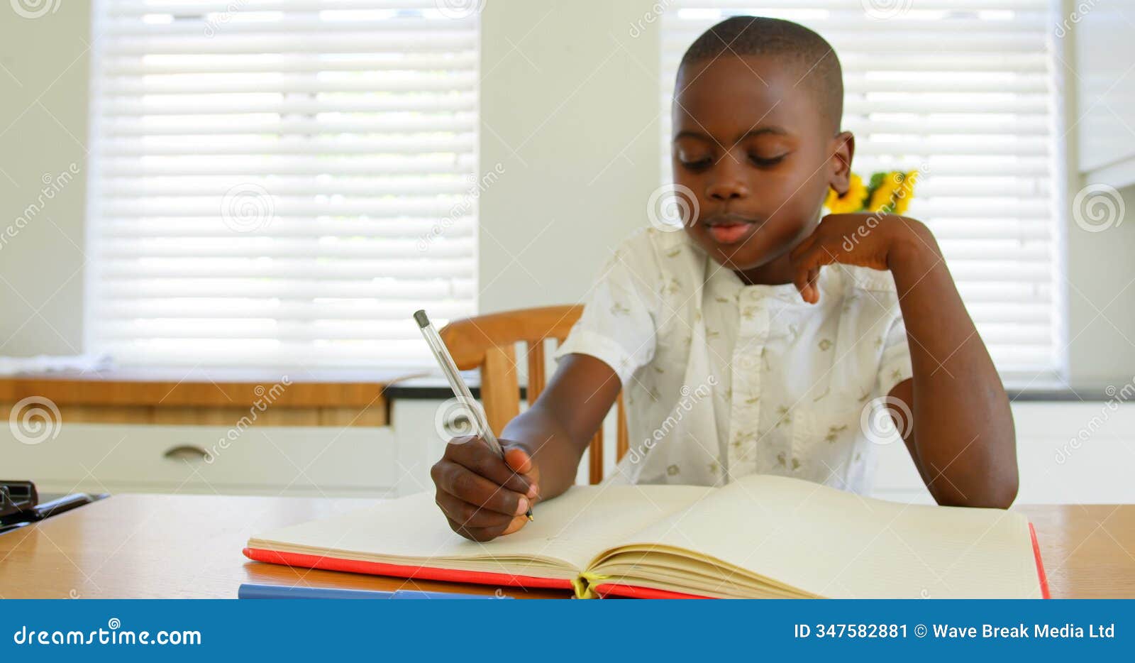 Front View of Little Black Boy Doing Homework at Dining Table in a ...