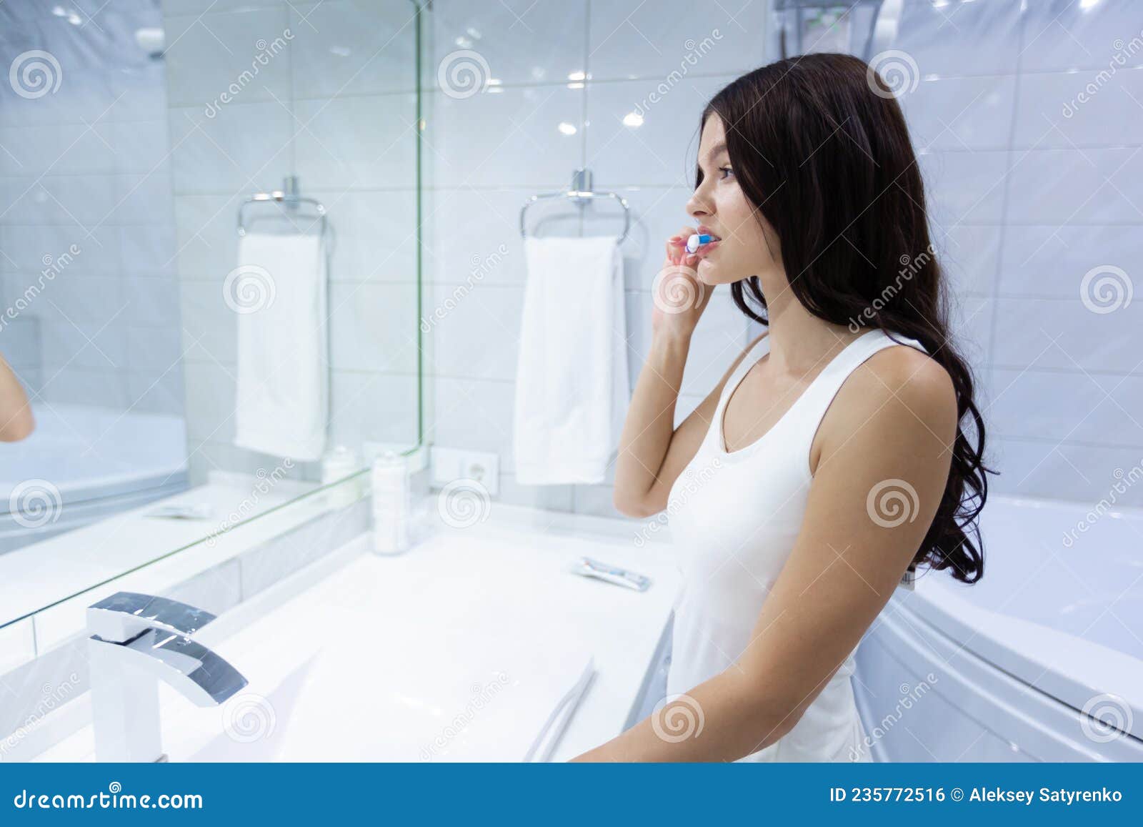 Front View Portrait Of Pretty Young Female Brushing Her Teeth In Front