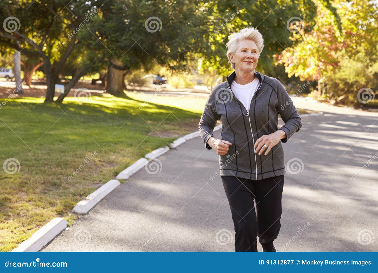 Front View of Senior Woman Jogging through Park Stock Image - Image of ...