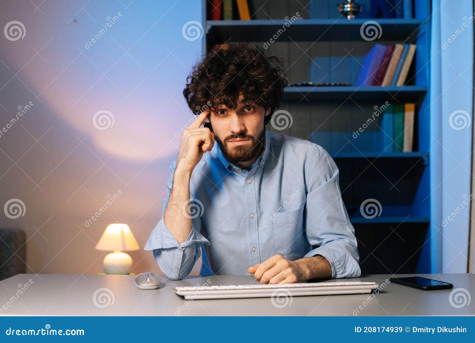Front View of Serious Young Man Sitting at Desk and Looking at Camera ...