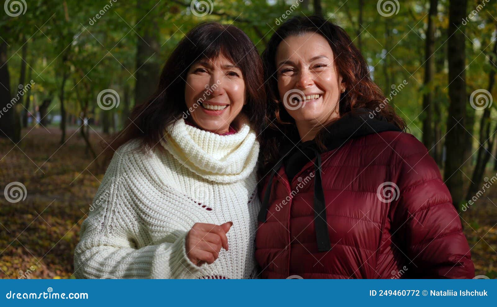 Front View Of Two Happy Mature Women With Toothy Smile Looking At