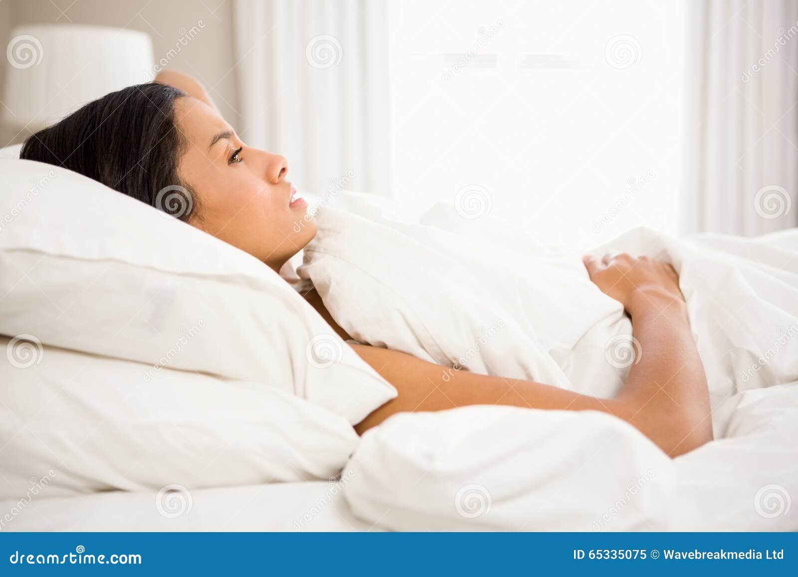 Frowning brunette in bed stock image. Image of beautiful - 65335075