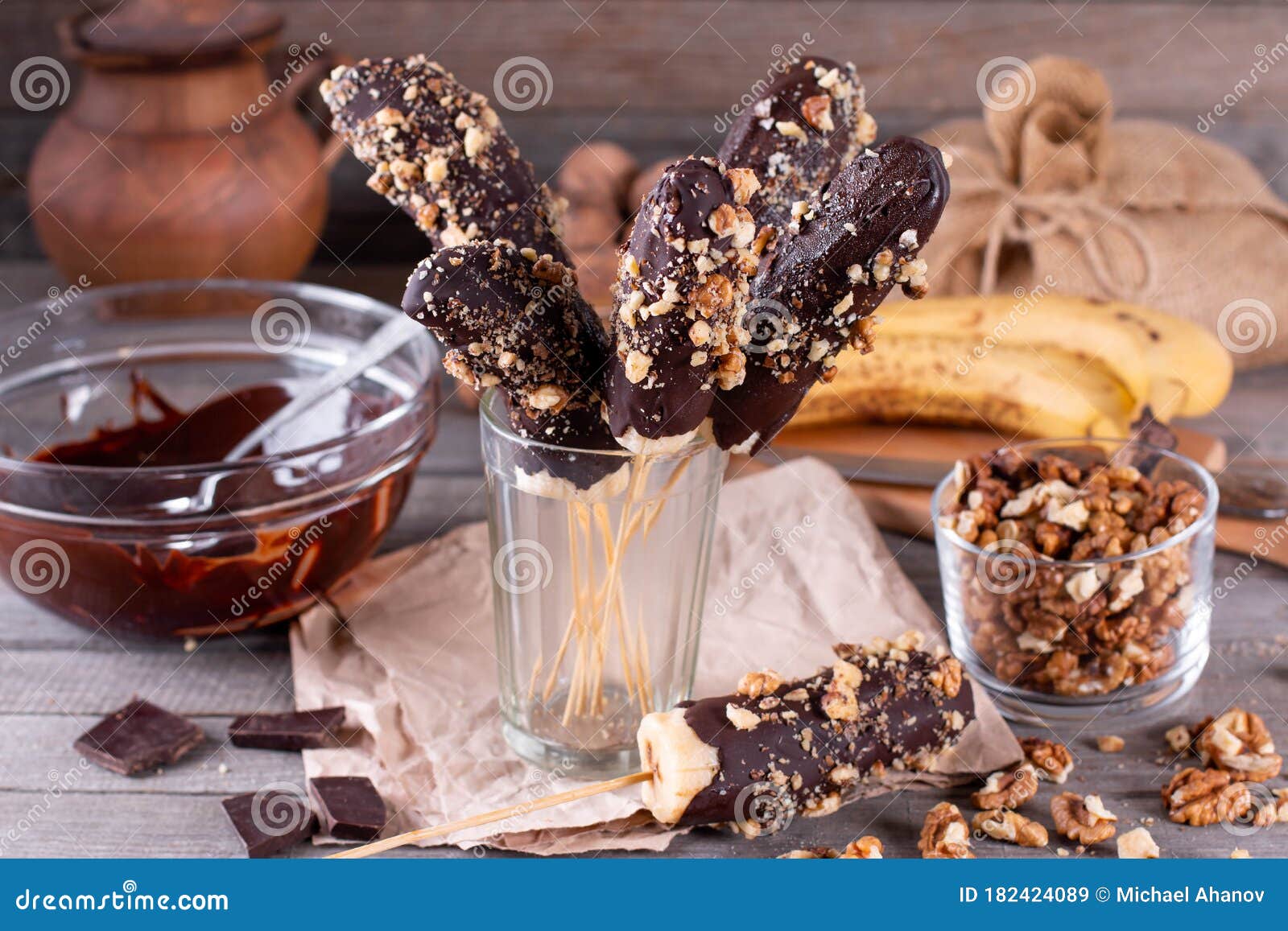 Frozen Chocolate Covered Bananas on a Stick in a Glass Beaker on Wooden ...
