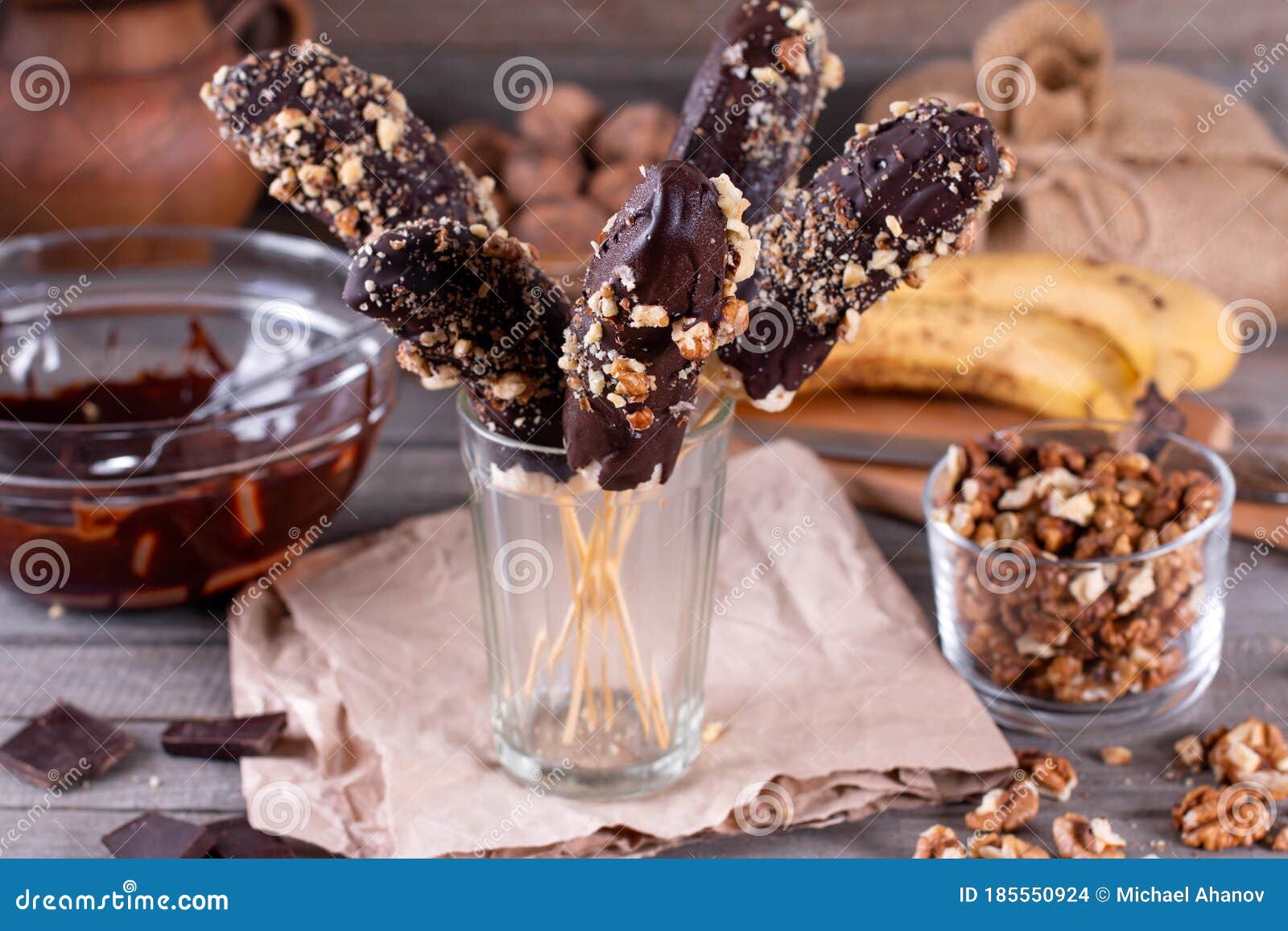 Frozen Chocolate Covered Bananas on a Stick in a Glass Beaker on Wooden ...