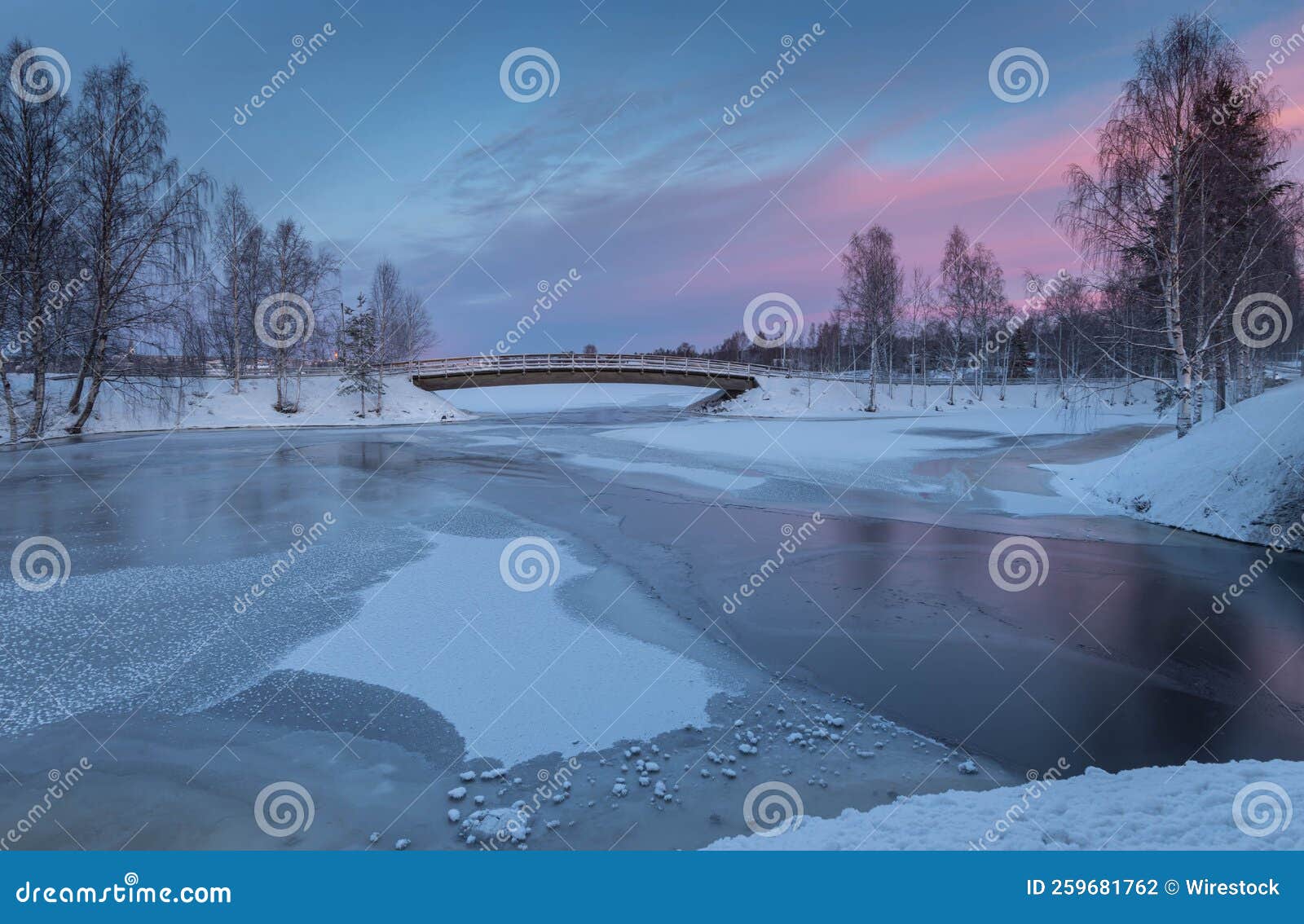 Frozen River with a Bridge Going Over it in Winter during a Sunset ...