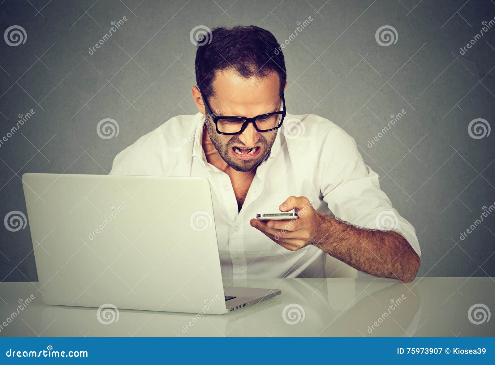 Frustrated Man with Laptop Texting on Mobile Phone Stock Image - Image ...