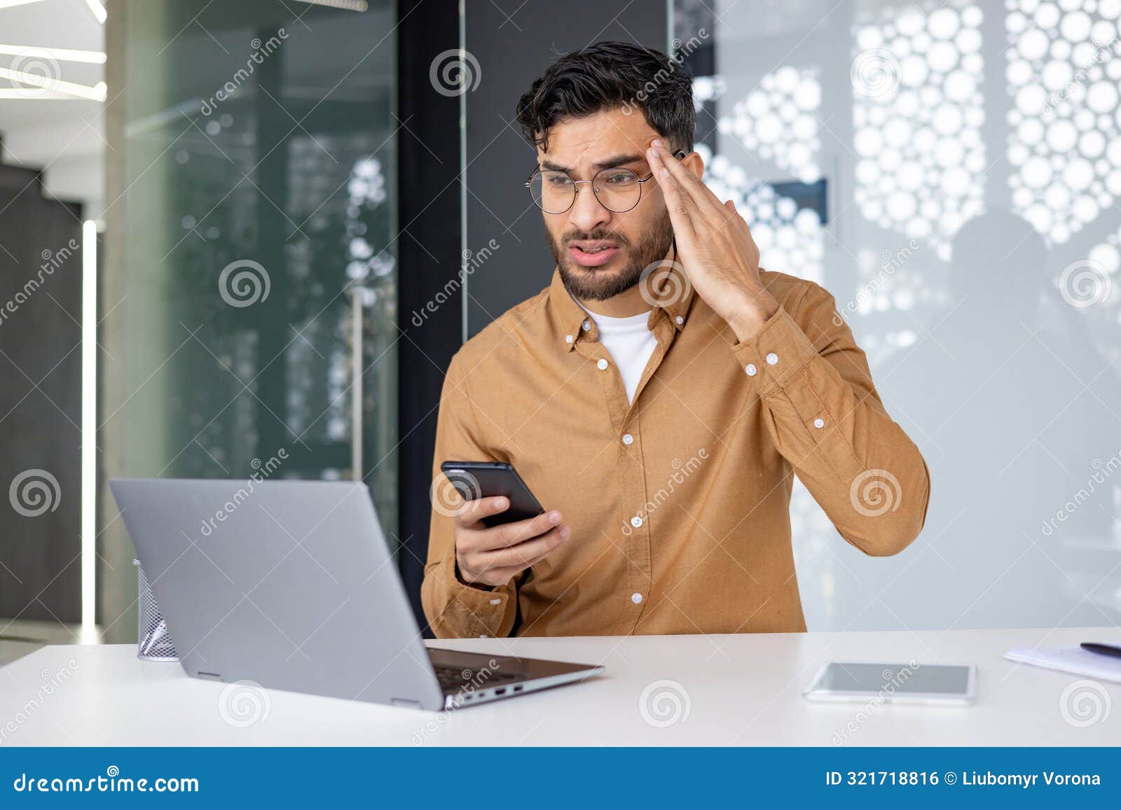 Frustrated Man Using Phone and Laptop in Office, Solving Problem ...