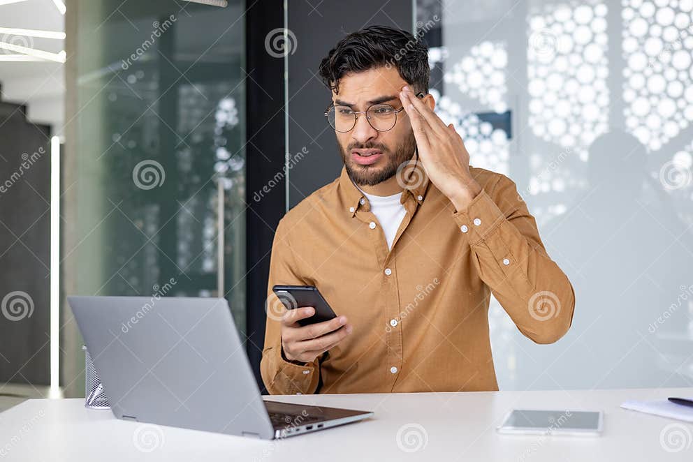 Frustrated Man Using Phone and Laptop in Office, Solving Problem ...