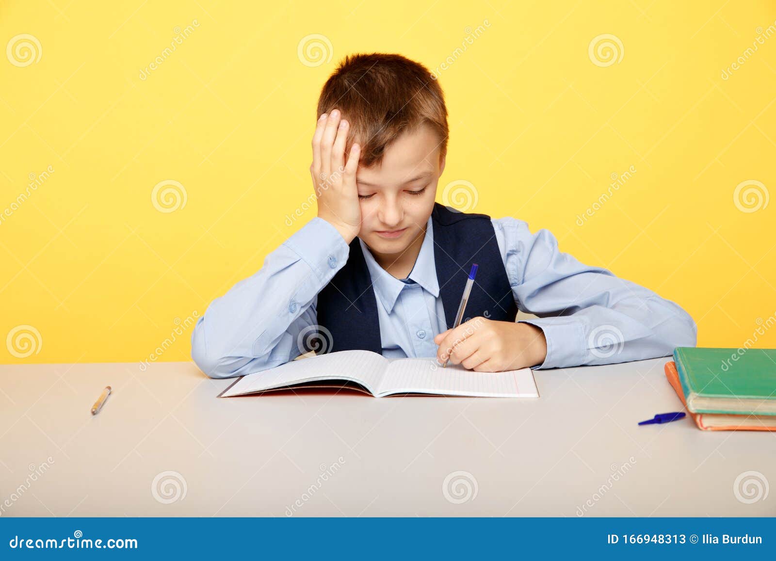 Frustrated Upset Boy at School Sitting at the Desk and Dotng Classwork ...