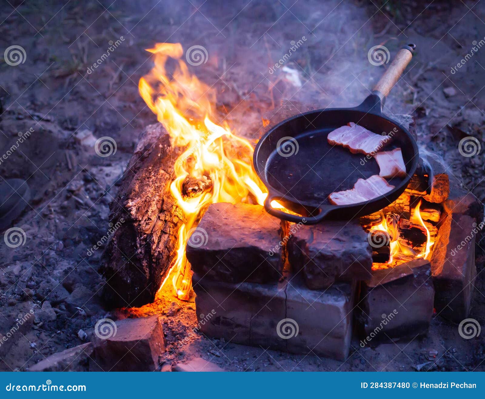 Frying Bacon in a Pan Over a Fire. Cooking Outdoors in the Evening ...