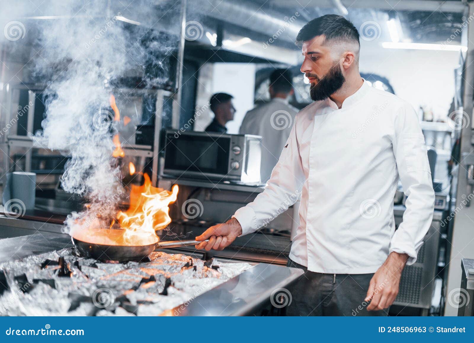 Frying Pan is on Fire. Chef in White Uniform Cooking Food at Kitchen ...