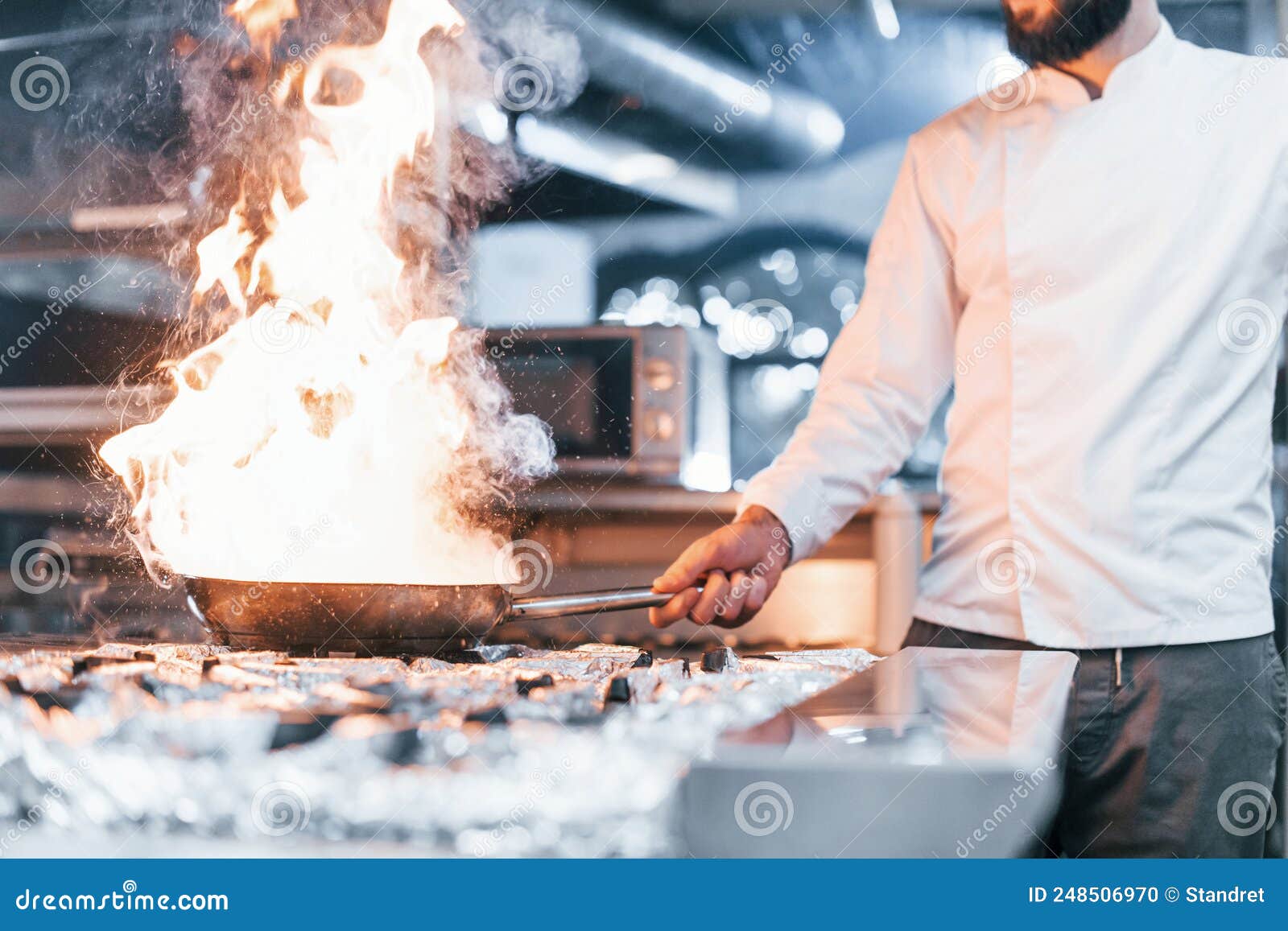 Frying Pan is on Fire. Chef in White Uniform Cooking Food at Kitchen ...