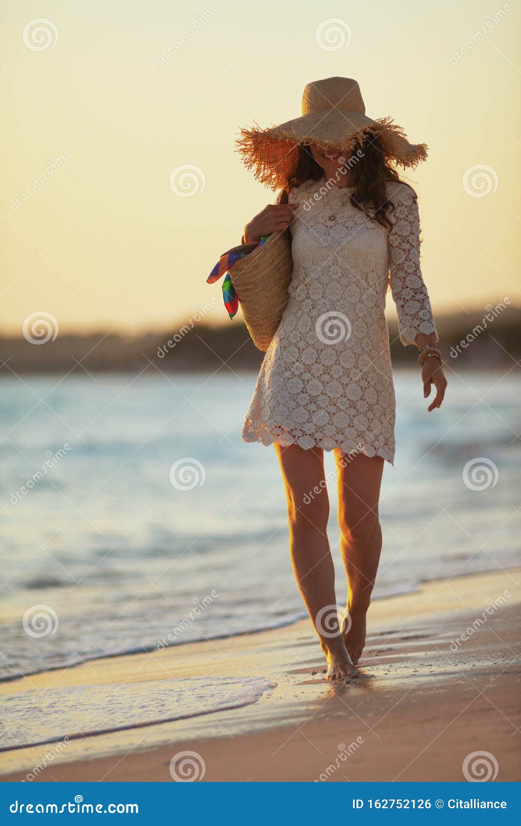 Smiling Elegant Woman on Ocean Coast at Sunset Walking Stock Photo ... Smiling Elegant Woman on Ocean Coast at Sunset Walking Stock Photo ...
