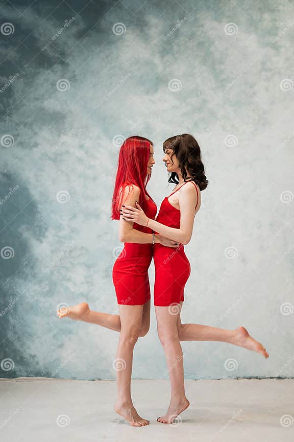 Full Length Portrait Of Two Tenderly Embracing Women Dressed In