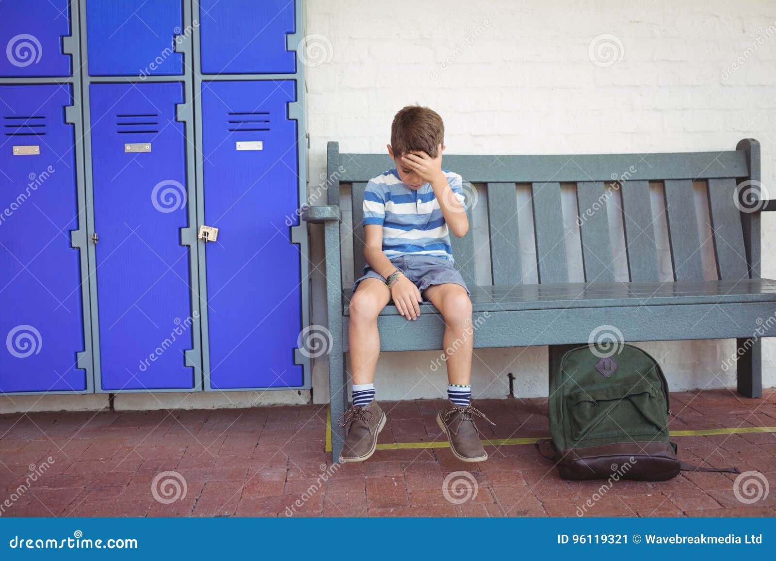 Full Length Of Sad Boy Sitting On Bench By Lockers Editorial Photo ...