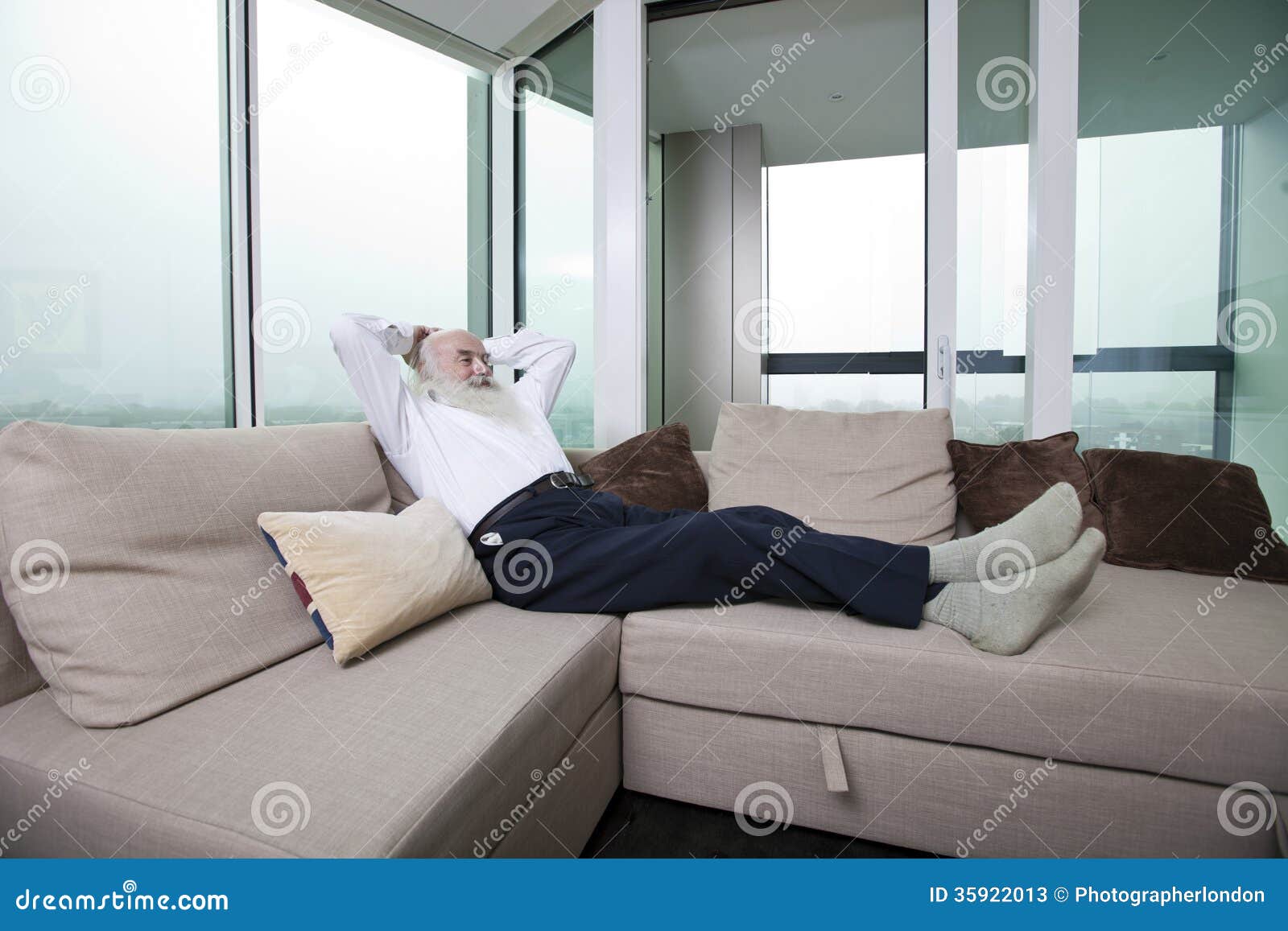 Full Length of Senior Man Relaxing on Sofa with Hands Behind Head at ...