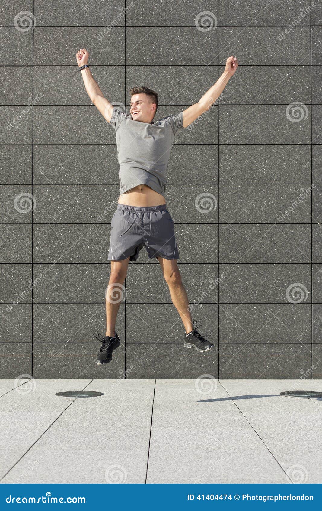 Full Length of Successful Jogger Jumping Against Tiled Wall Stock Photo ...
