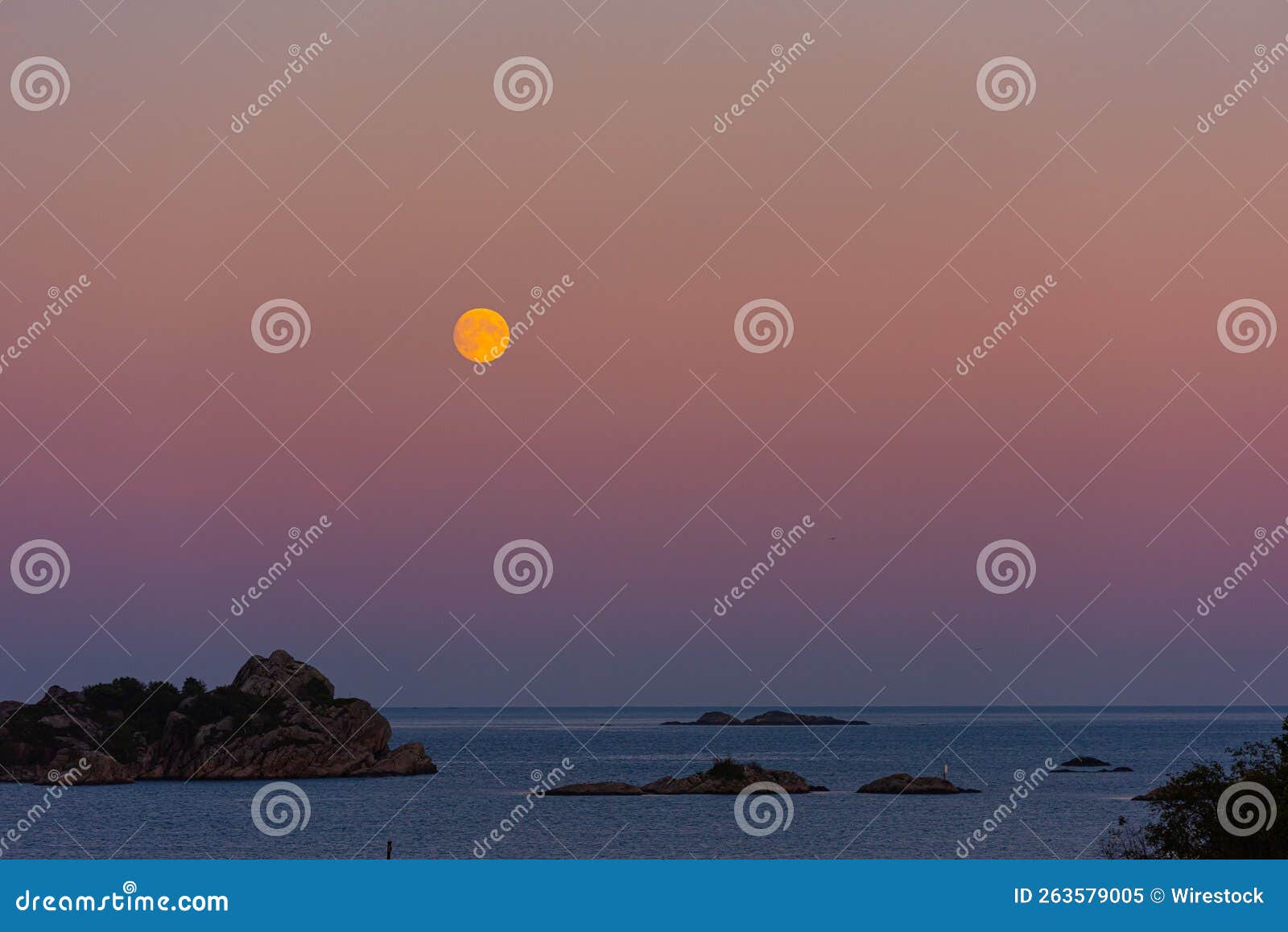 Full Moon Rising Over the Ocean in a Pinkish and Cloudless Sky Stock ...