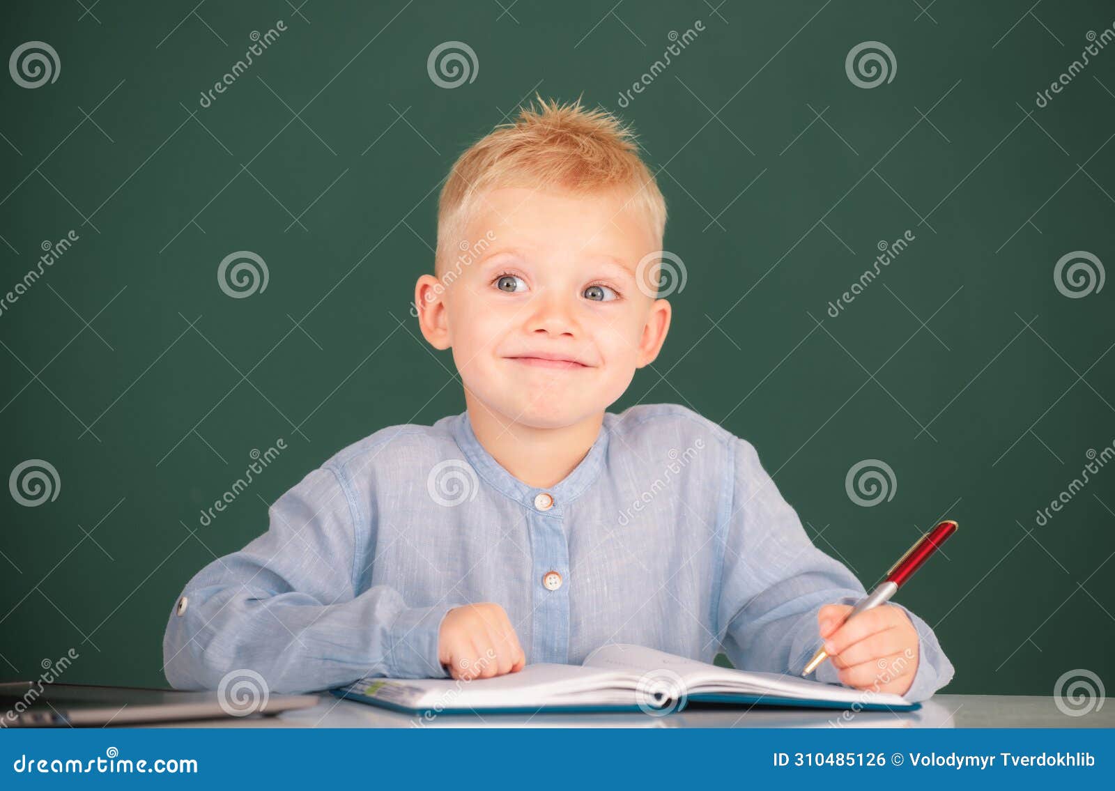 Funny Kid Writing in Notebook in Class. Child at School. Kid is ...