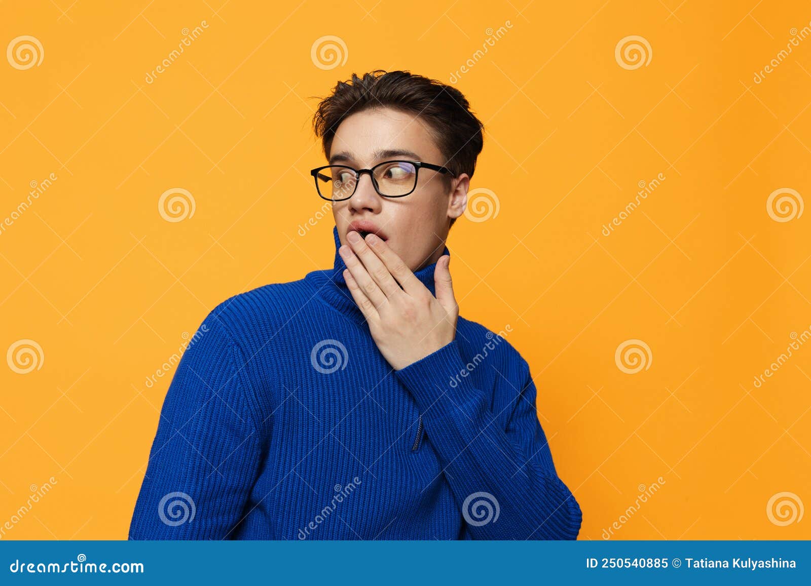 A Funny Shocked Man Stands In Glasses A Blue Zip Up Jacket And Holds